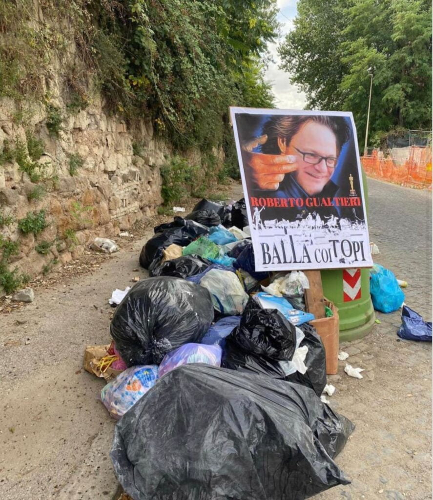 Roma, sul cassonetto strapieno di spazzatura compare un cartello ...